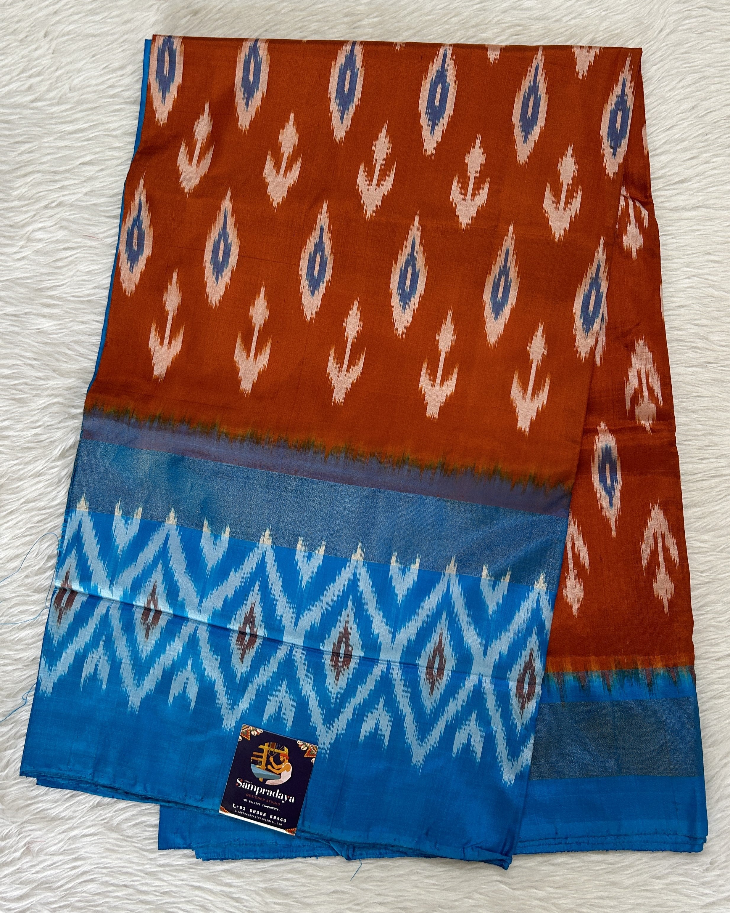 Ikkat Pattu Saree Rust Orange colored Saree complemented with a Blue C ...